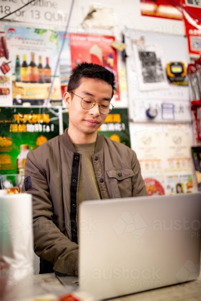 Image of Happy Asian grocery store manager working at his laptop at the ...
