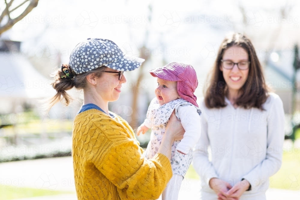 Image of Happy aunty playing with baby niece outside wearing hats ...