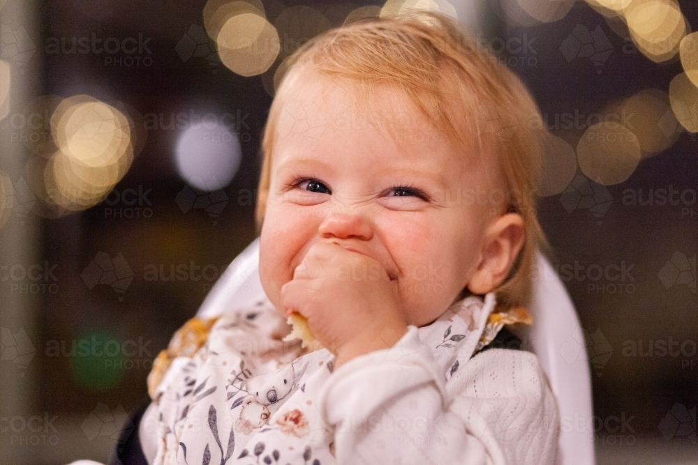 Image of Happy baby eating food at a restaurant smiling at camera late ...