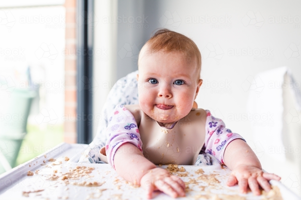 Image of Happy baby in high chair making a mess with food at breakfast ...