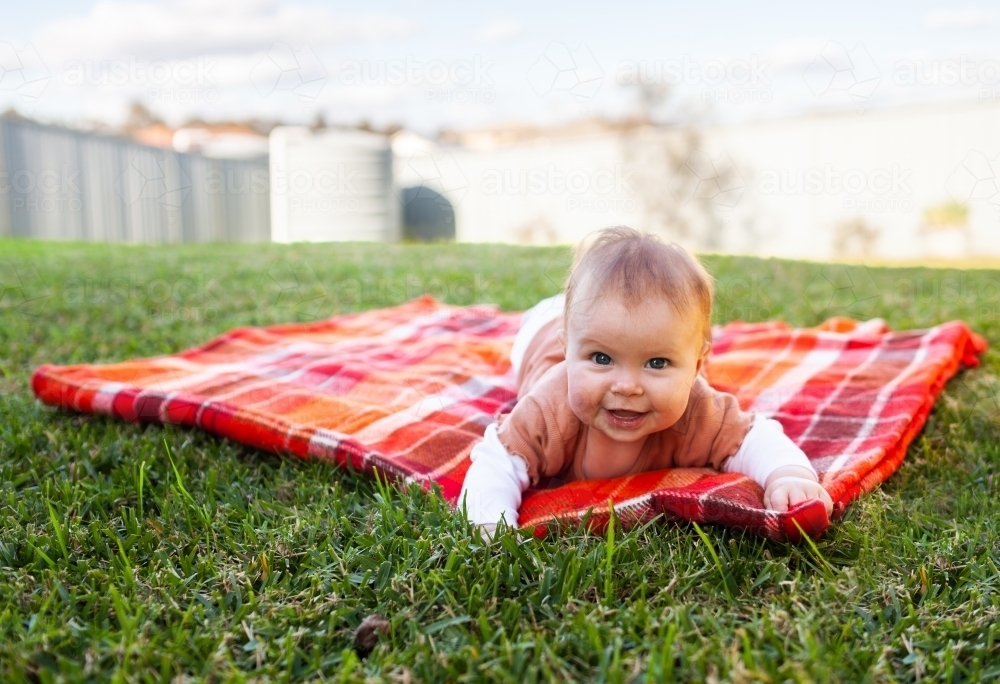 Image of Happy baby outside on picnic mat in backyard of suburban home ...