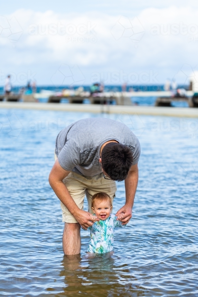 Image of Happy baby standing in sea water in ocean pool at first trip ...