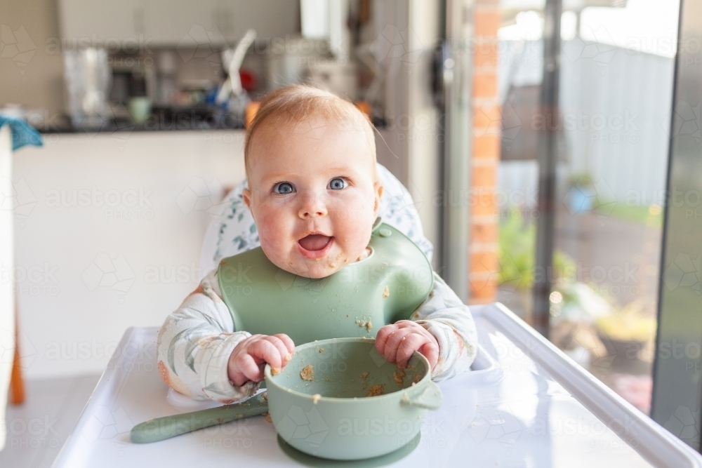 Image of Happy baby trying food for the first time sitting up in high ...