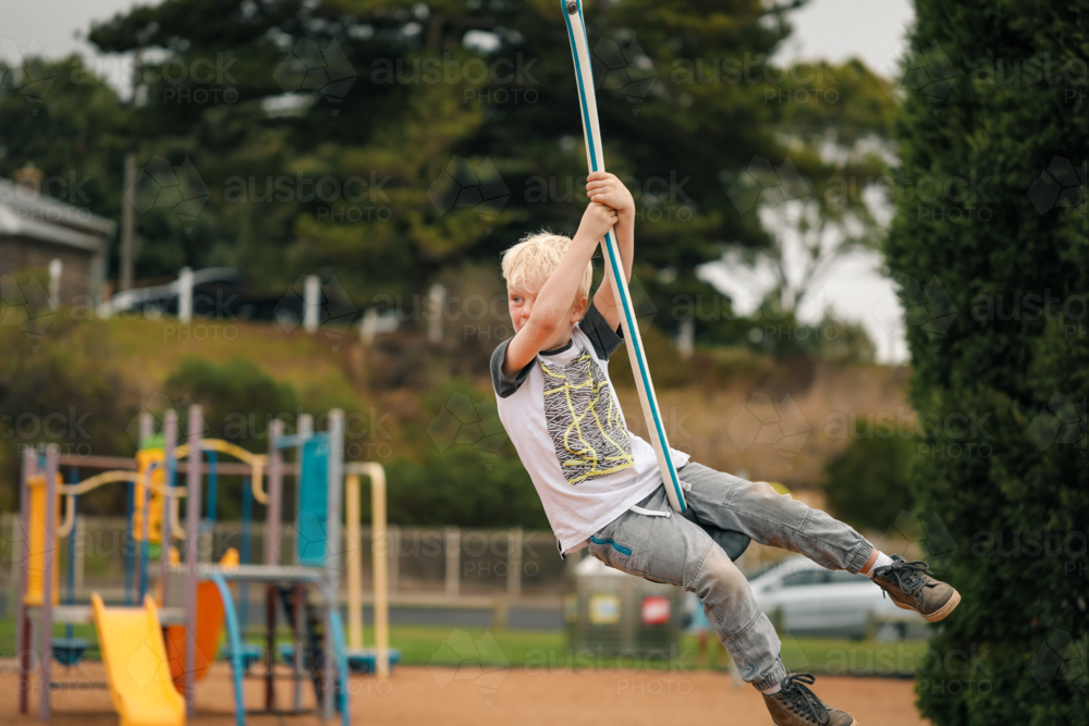 Image of Happy boy playing on swing at the playground - Austockphoto