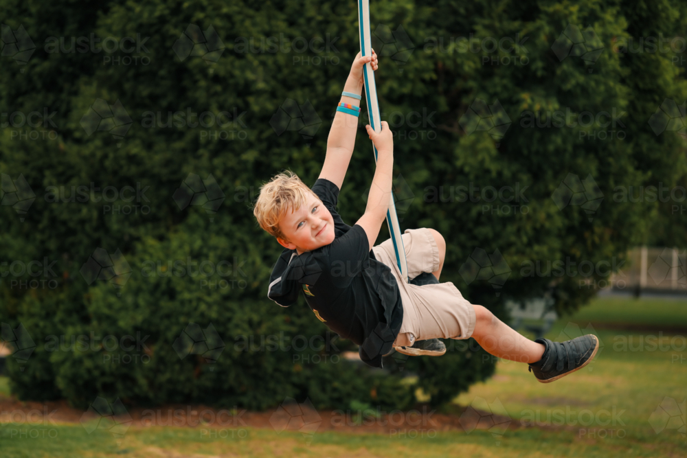 Image of Happy boy playing on swing at the playground - Austockphoto