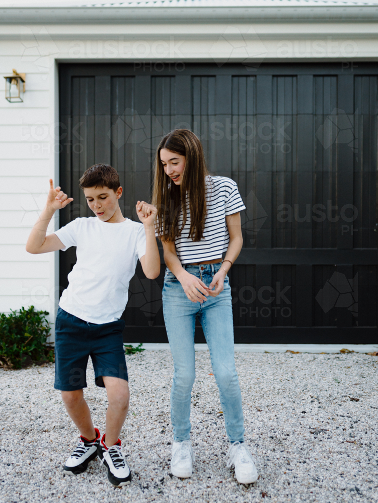 Image of Happy brother and teen sister being silly together outside carport at home - Austockphoto