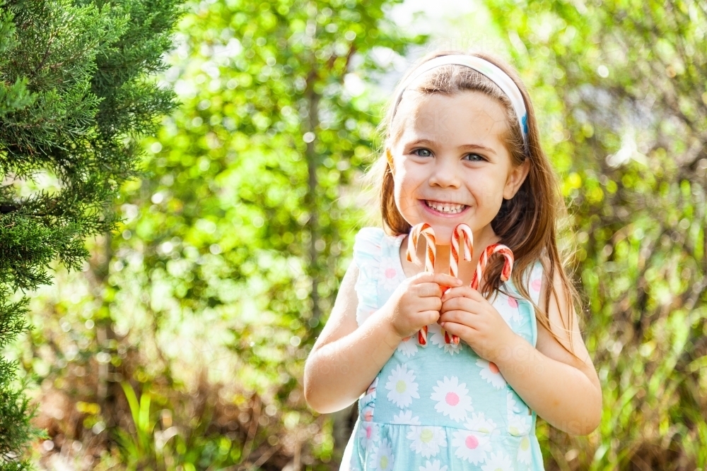 Image of Happy child holding up candy canes outside - Austockphoto
