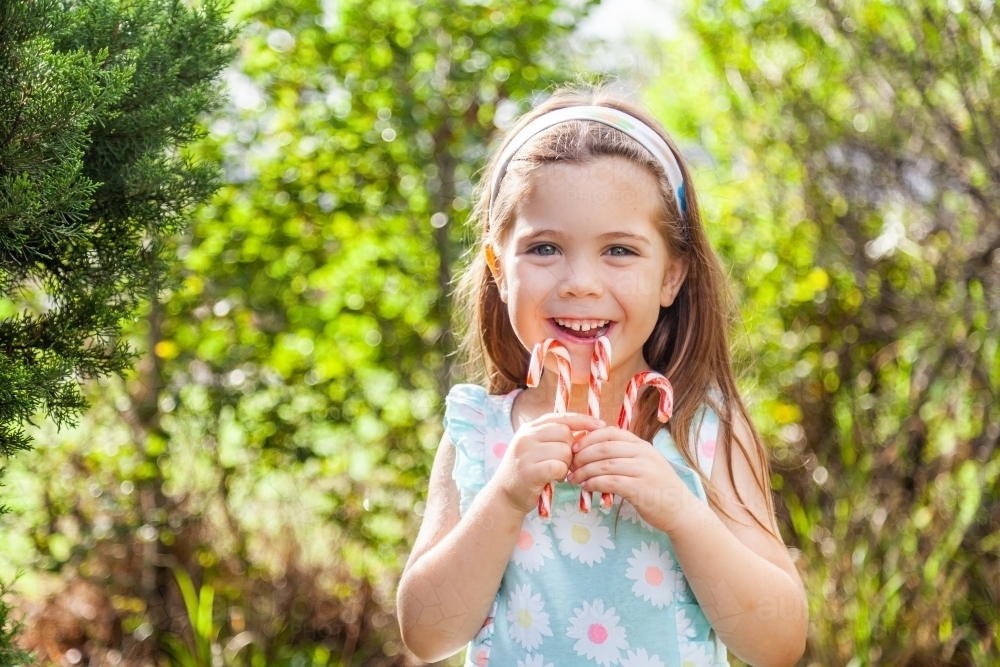 Image of Happy child holding up candy canes outside - Austockphoto