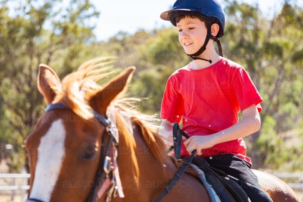 Image of Happy child in red riding horse in bush - Austockphoto