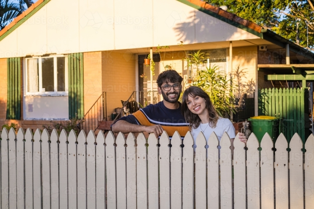 Image of happy couple in front of their home - Austockphoto