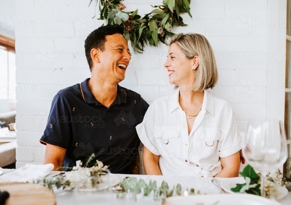 Image of Happy couple smiling with each other on the table. - Austockphoto