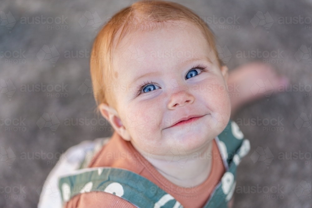 Image of happy eight month old baby sitting outside on concrete ...