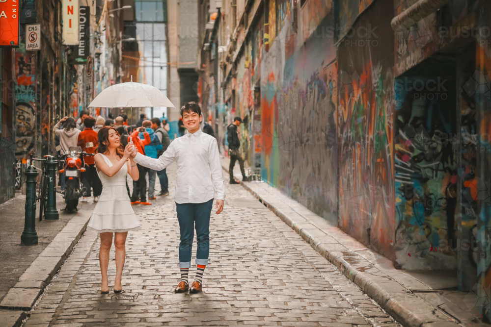 Image of Happy engaged couple posing with white umbrella in Hosier Lane ...