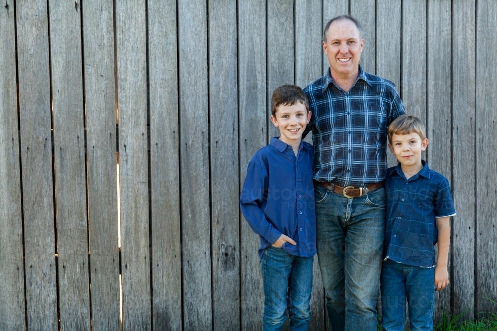 Image of Happy father standing with two young sons - Austockphoto