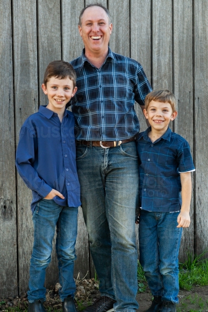 Image of Happy father standing with two young sons - Austockphoto