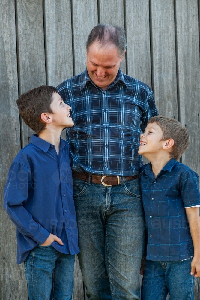 Image of Happy father standing with two young sons - Austockphoto