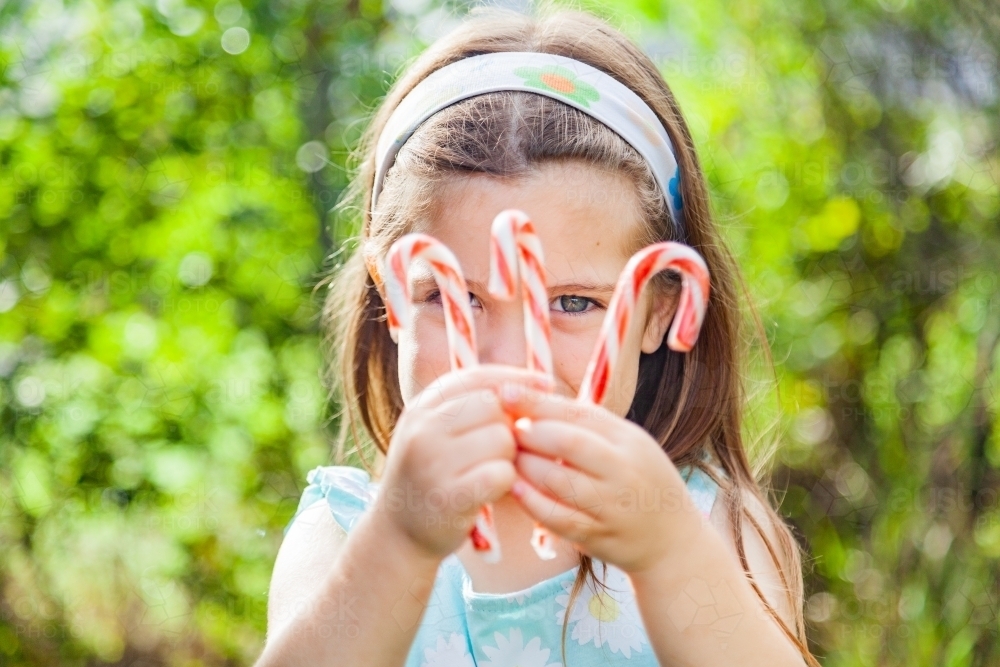 Image of Happy girl holding up traditional coloured candy canes at ...