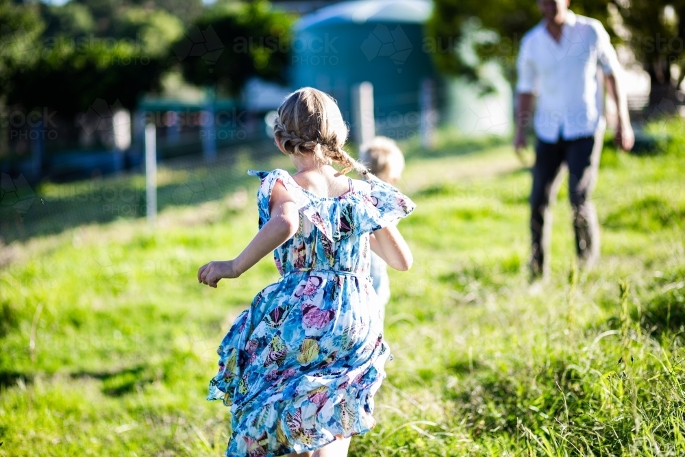 Image of Happy girl running through long grass to see her father ...