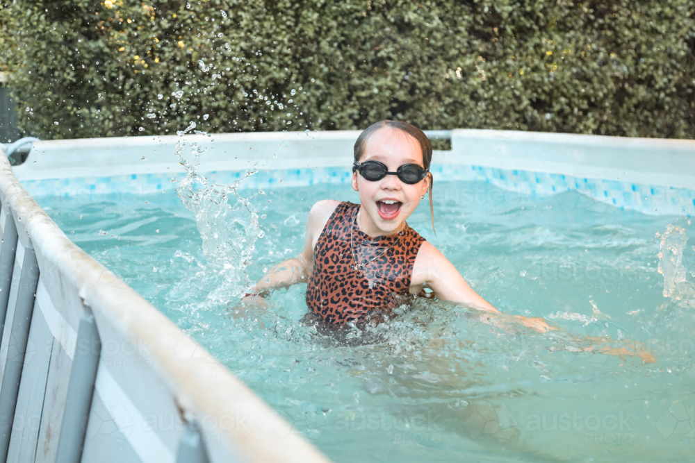 Image of Happy girl swimming in backyard pool - Austockphoto