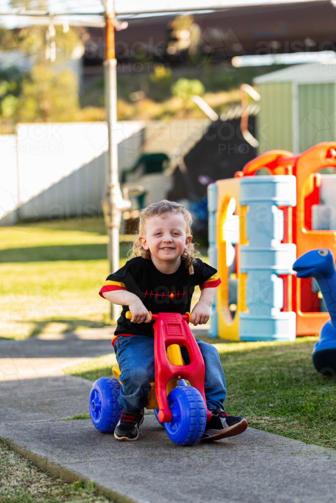 Image of Happy little Aussie kid playing with colourful trike in ...