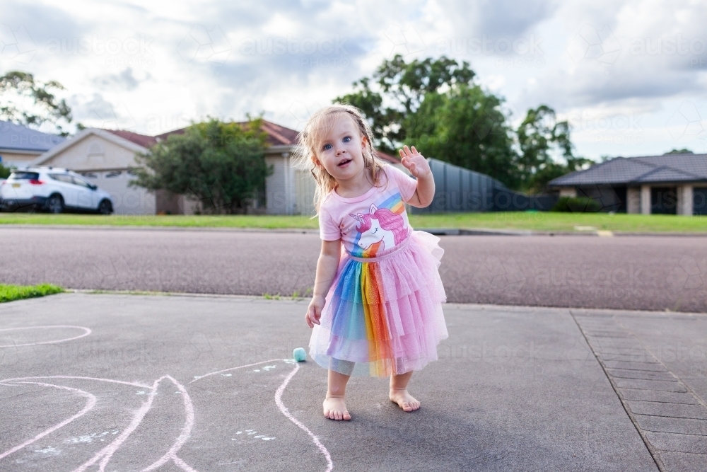 Image of Happy little girl dancing on suburban driveway with chalk ...