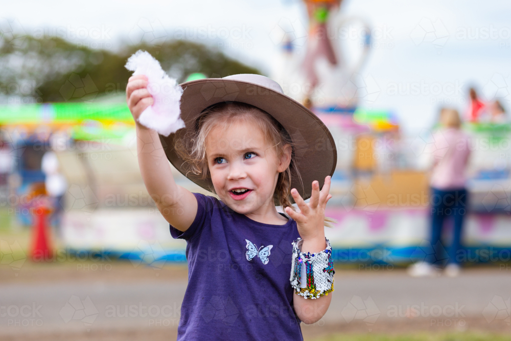 Image of Happy little girl eating pink fairy floss as a treat at local ...