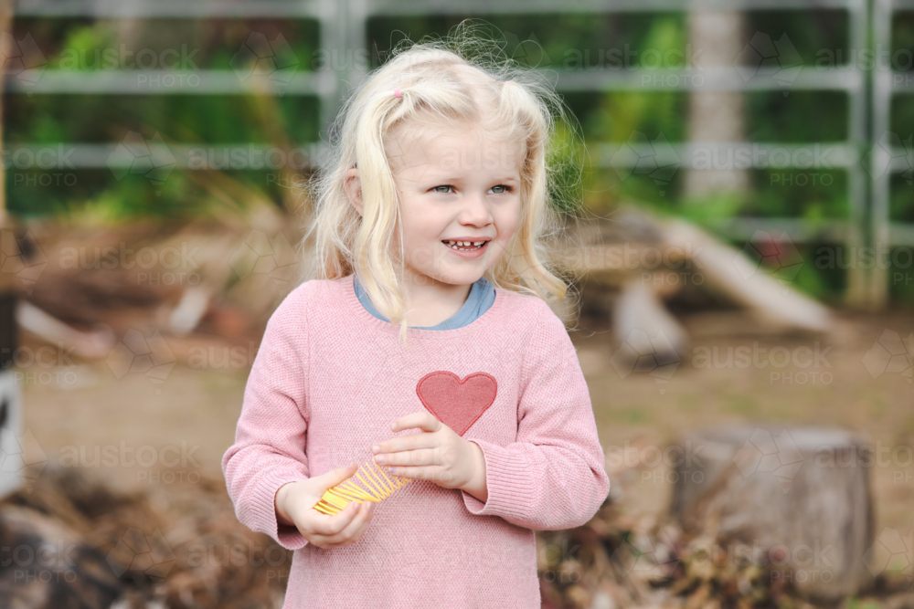 Image of Happy little girl playing with slinky toy in the garden ...