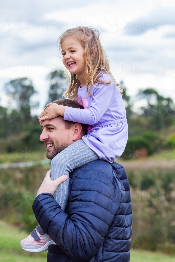 Image of Happy little girl riding on her dads shoulders on cold ...