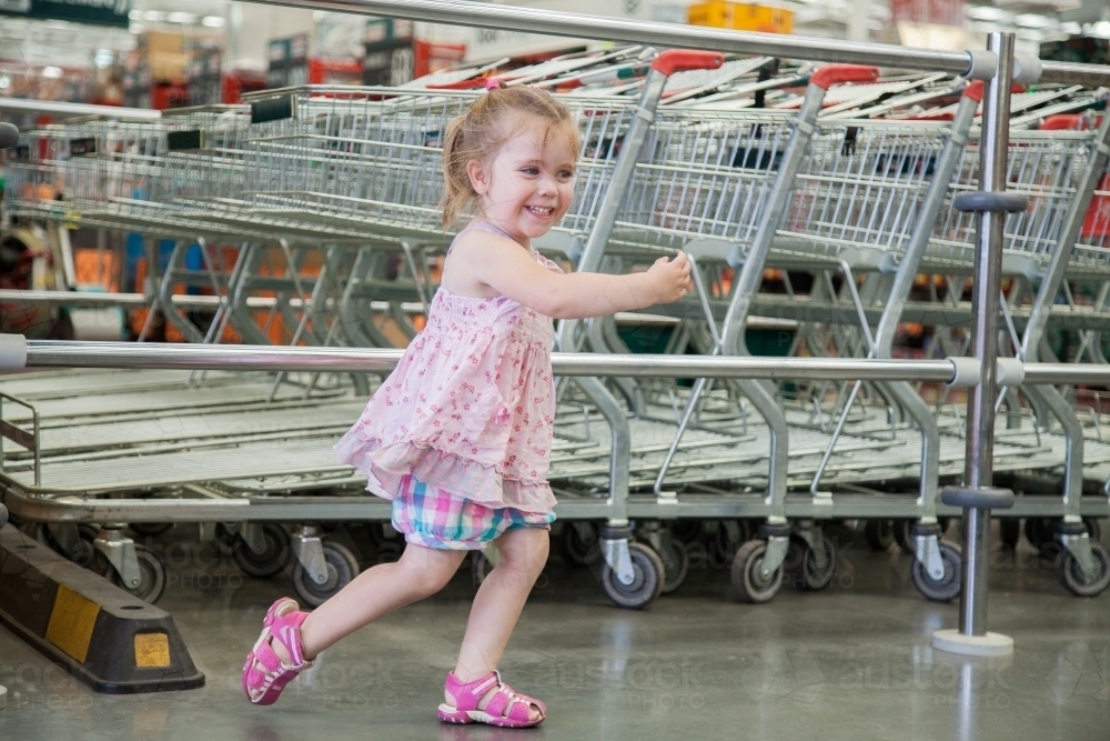 Image of Happy little girl running around in the shops - Austockphoto