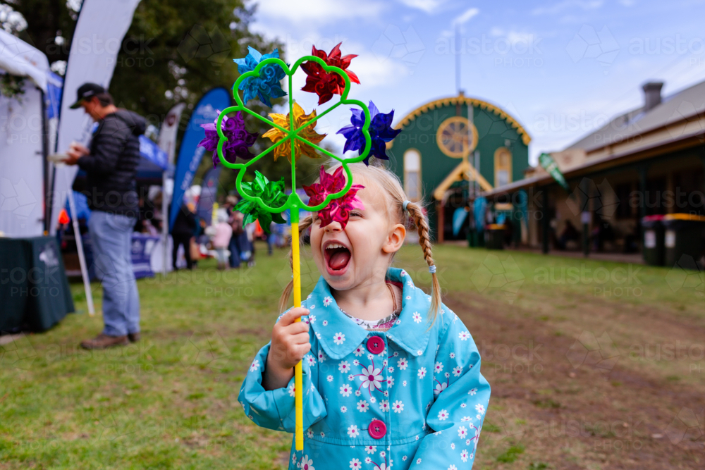 Image of Happy little kid in blue rain jacket playing with pinwheel at ...