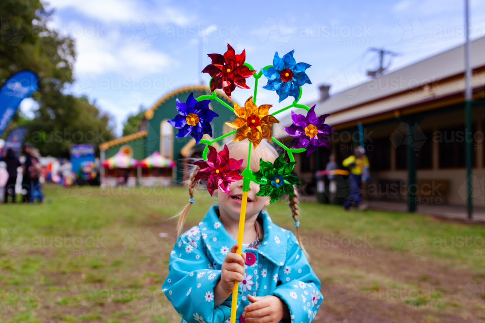 Image of Happy little kid in blue rain jacket playing with pinwheel at ...