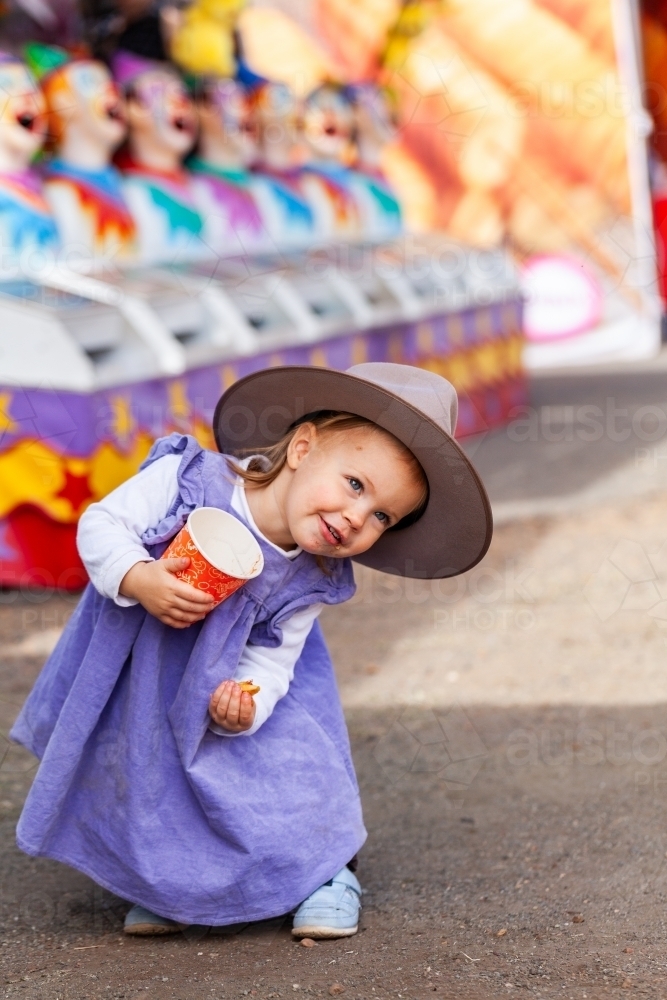 Image of Happy little toddler girl at showground eating cup of hot ...