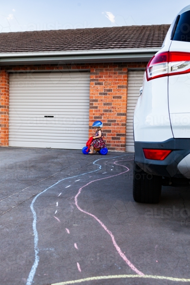 Image of Happy little toddler girl riding trike on chalk tracks drawn ...