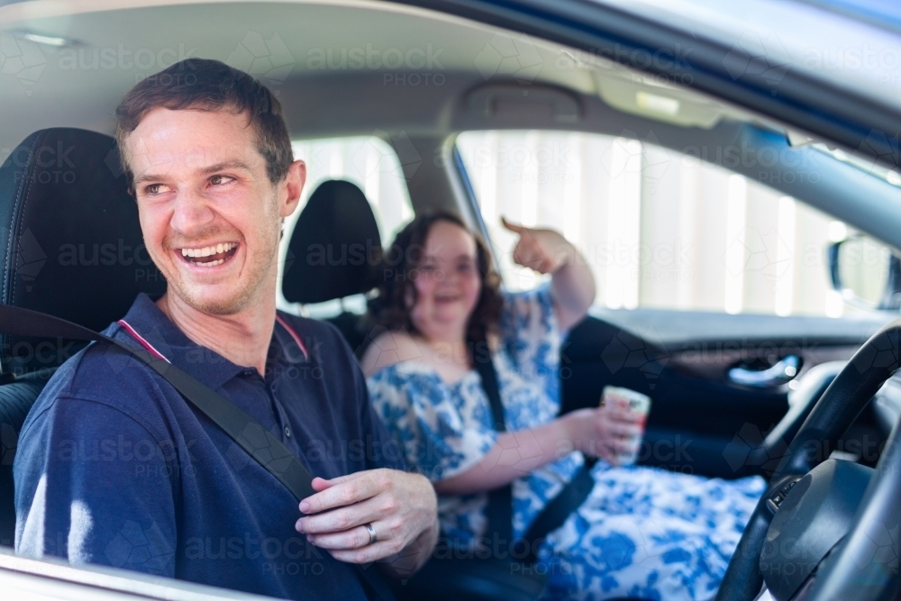 Image of Happy male NDIS provider driving car laughing and assisting ...