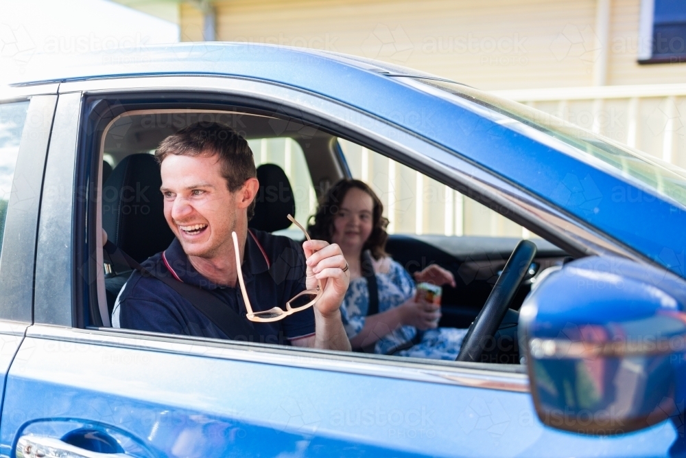 Image of Happy male NDIS provider driving car laughing and assisting ...