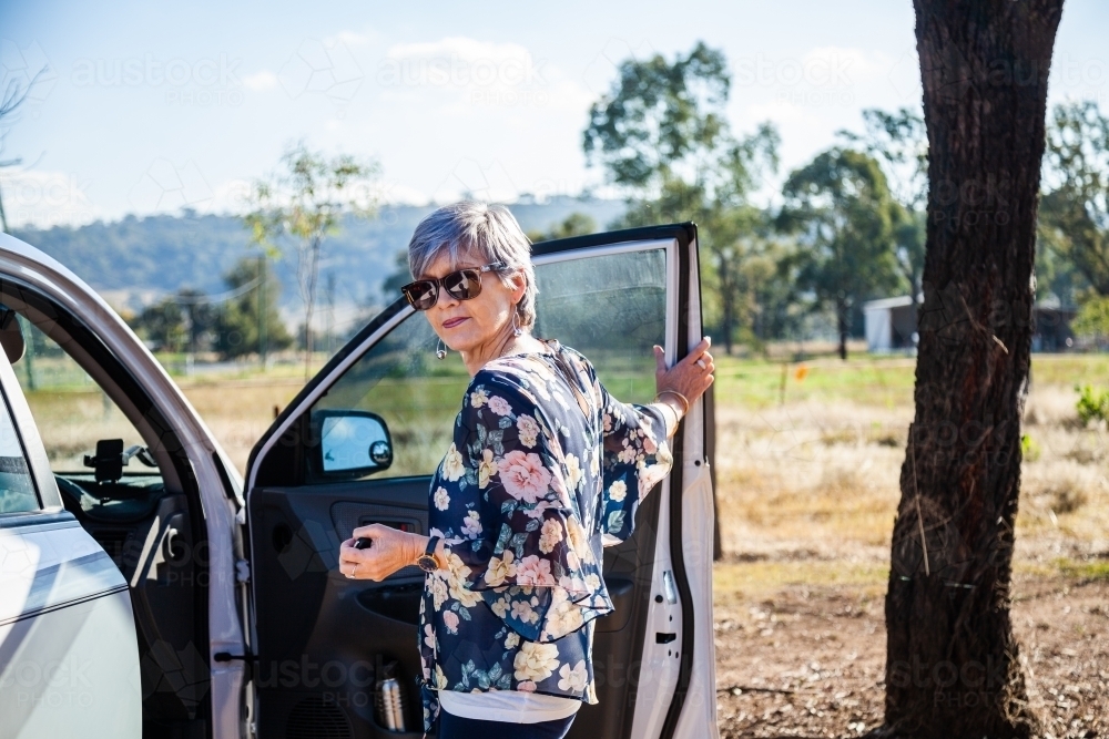 Image of Happy mature aged woman getting into her car - Austockphoto