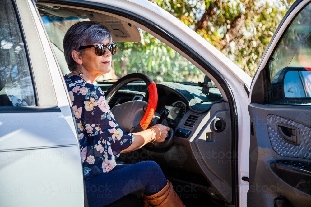 Image of Happy mature aged woman getting into her car - Austockphoto