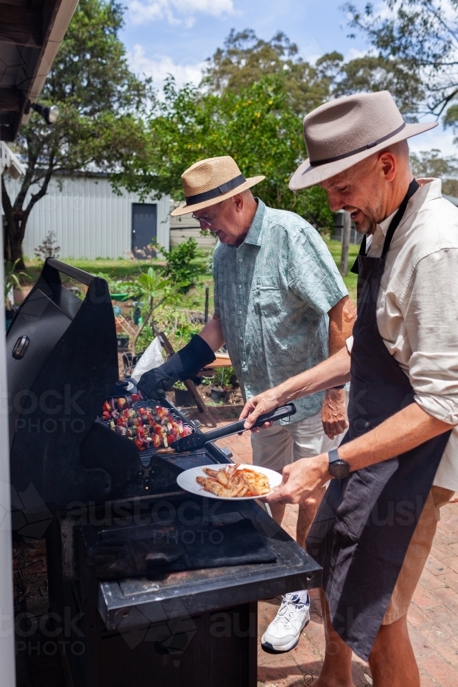 Image of happy men cooking lunch food on bbq in backyard of country ...