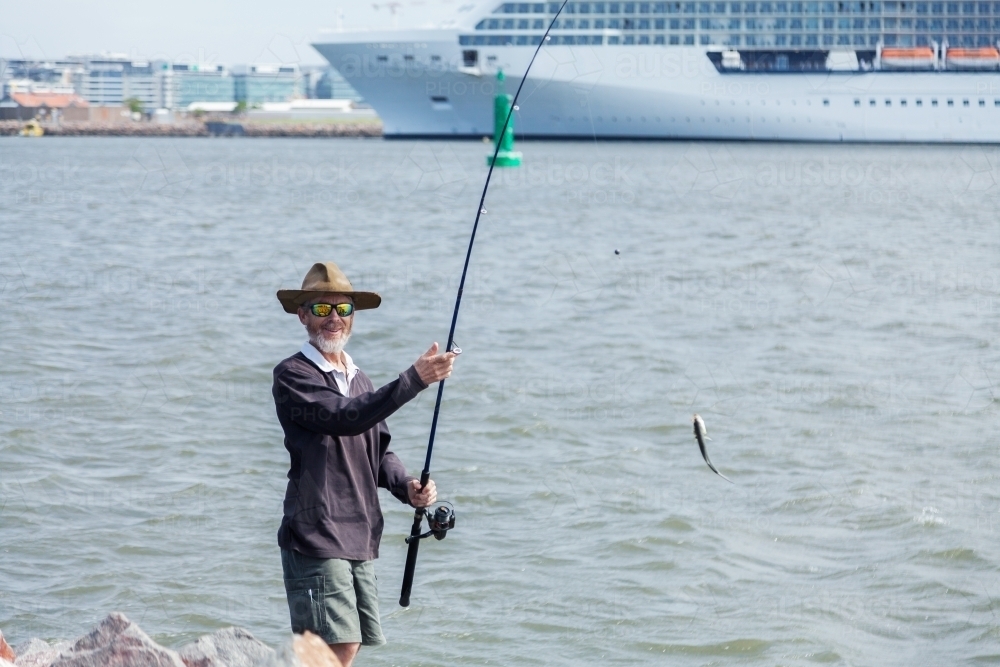 Image of Happy middle aged aussie man catching fish with a rod off the ...