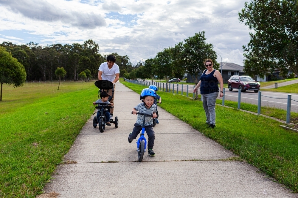 Image of Happy mixed race Aussie family riding balance bikes and ...