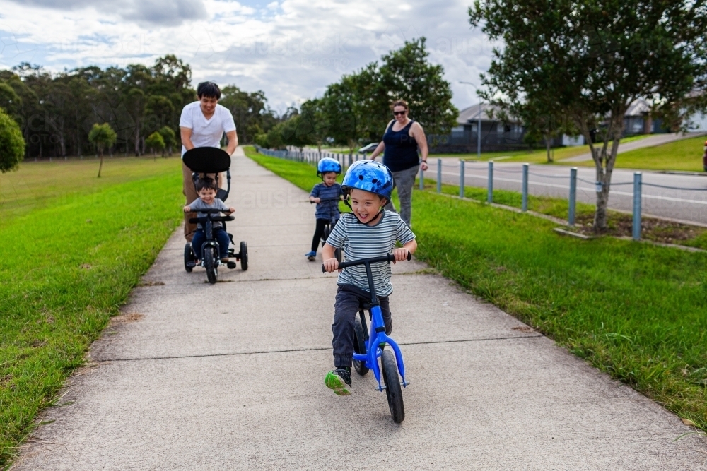 Image of Happy mixed race Aussie family riding balance bikes and ...