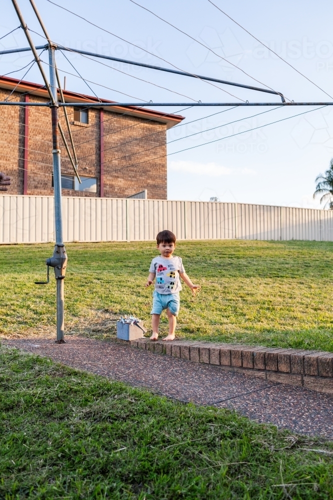 Image of Happy mixed race toddler in backyard with peg basket under ...