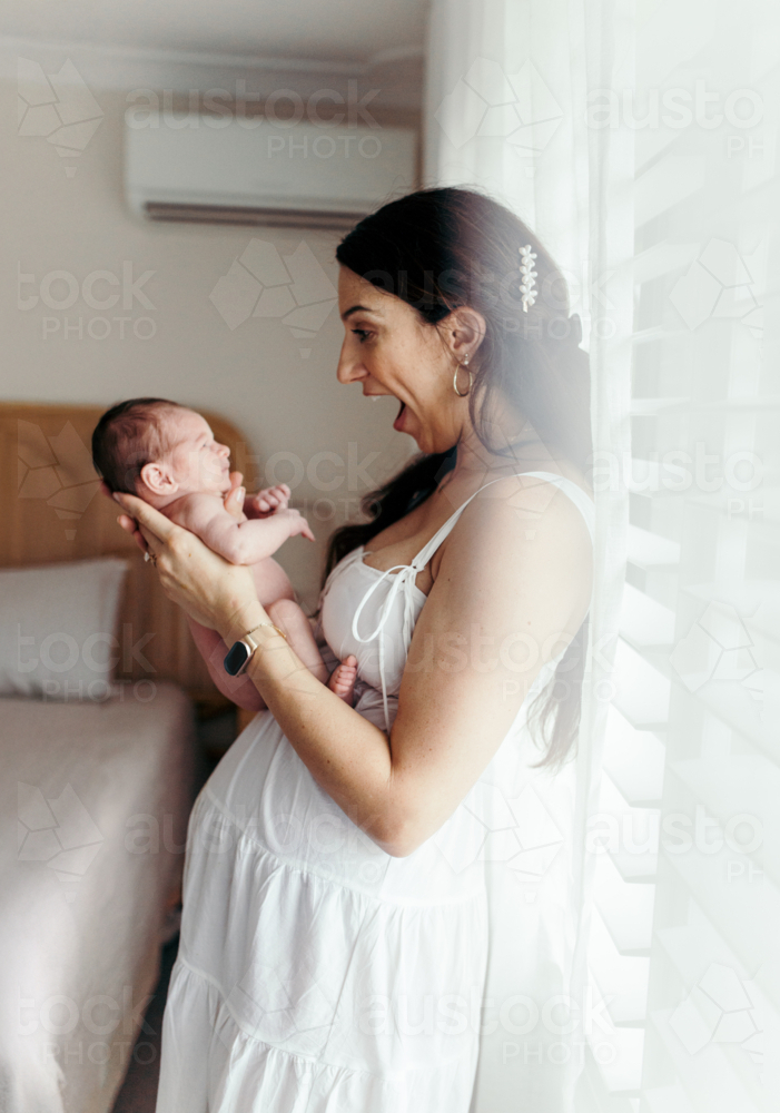 Image of Happy mother standing beside window holding newborn baby ...