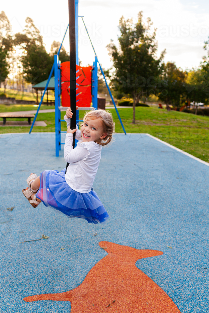 Image of Happy preschool aged child clinging tight to flying fox play ...