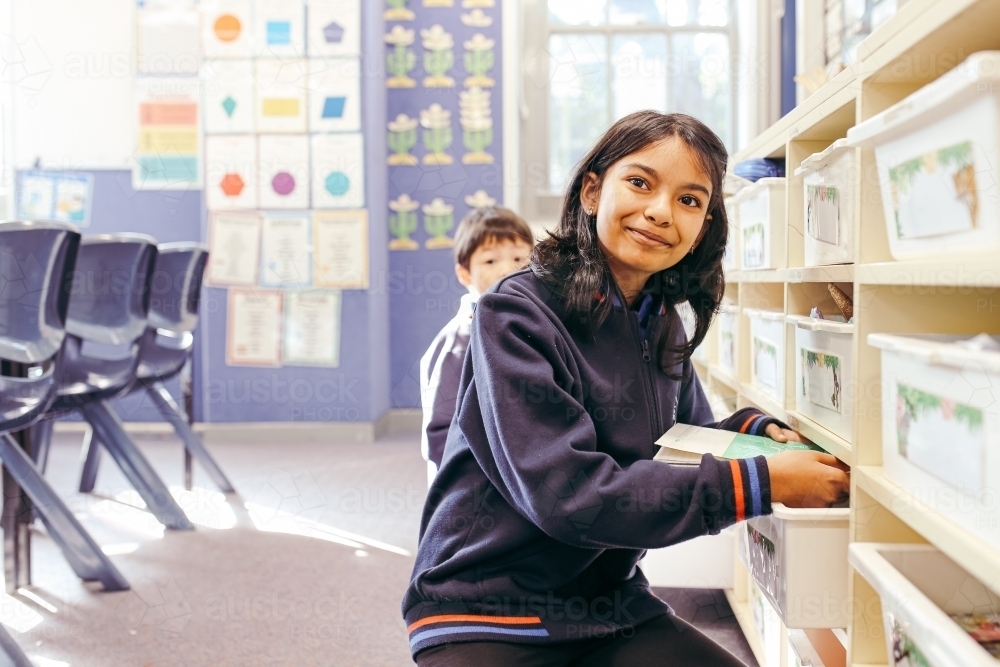 Image of Happy primary school student putting her work in her personal ...