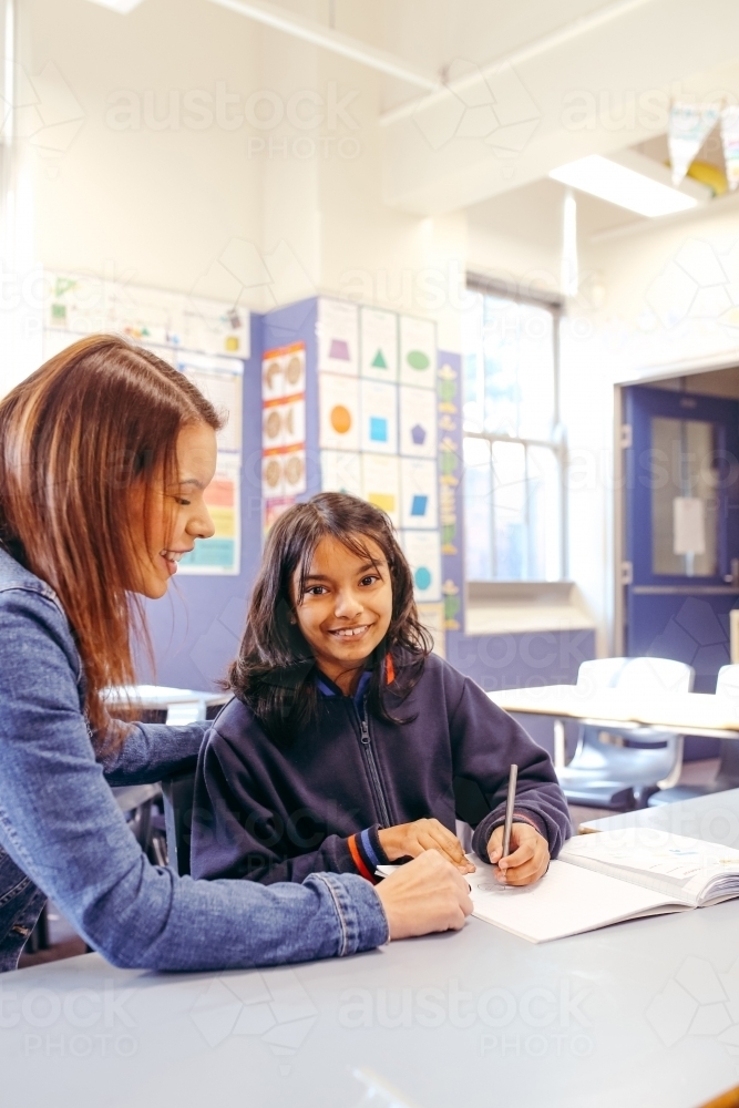 Image of Happy primary school student sitting with her teacher at her ...