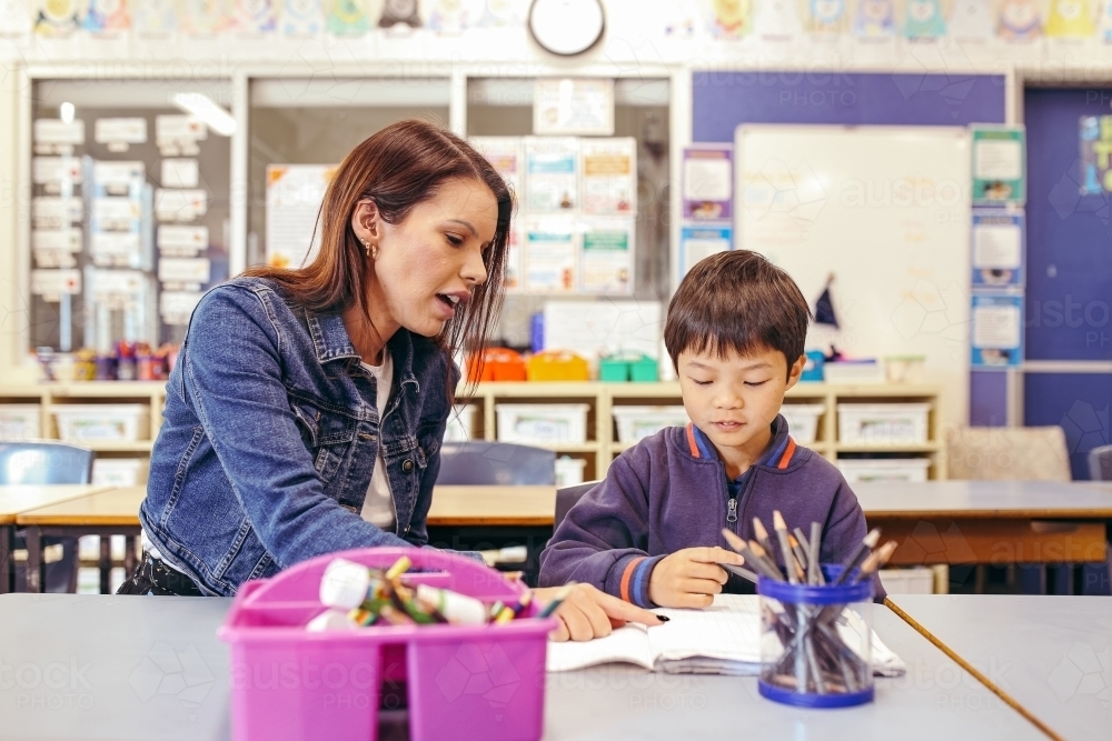 Image of Happy primary school student working with teacher - Austockphoto