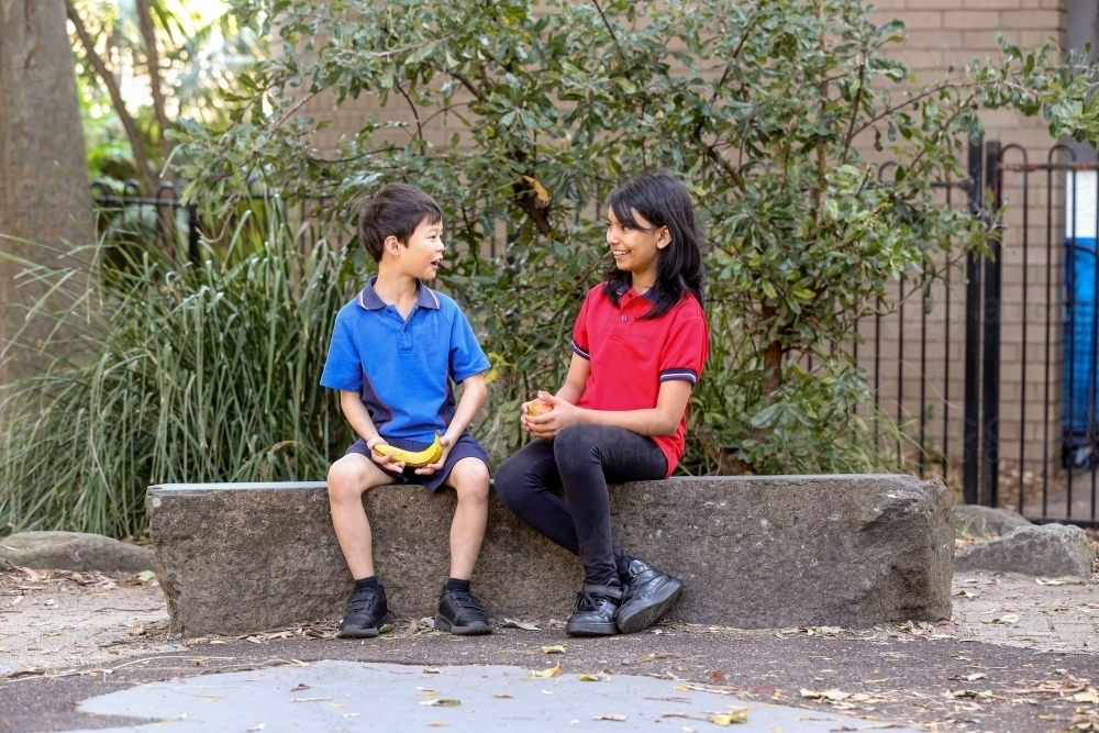 Image of Happy primary school students on fruit break - Austockphoto