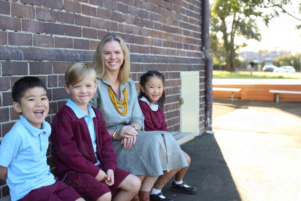 Image of Happy school children sitting with their teacher in the school ...