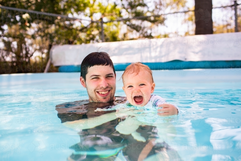 Image of Happy smiles on baby and dad in pool together in summer ...